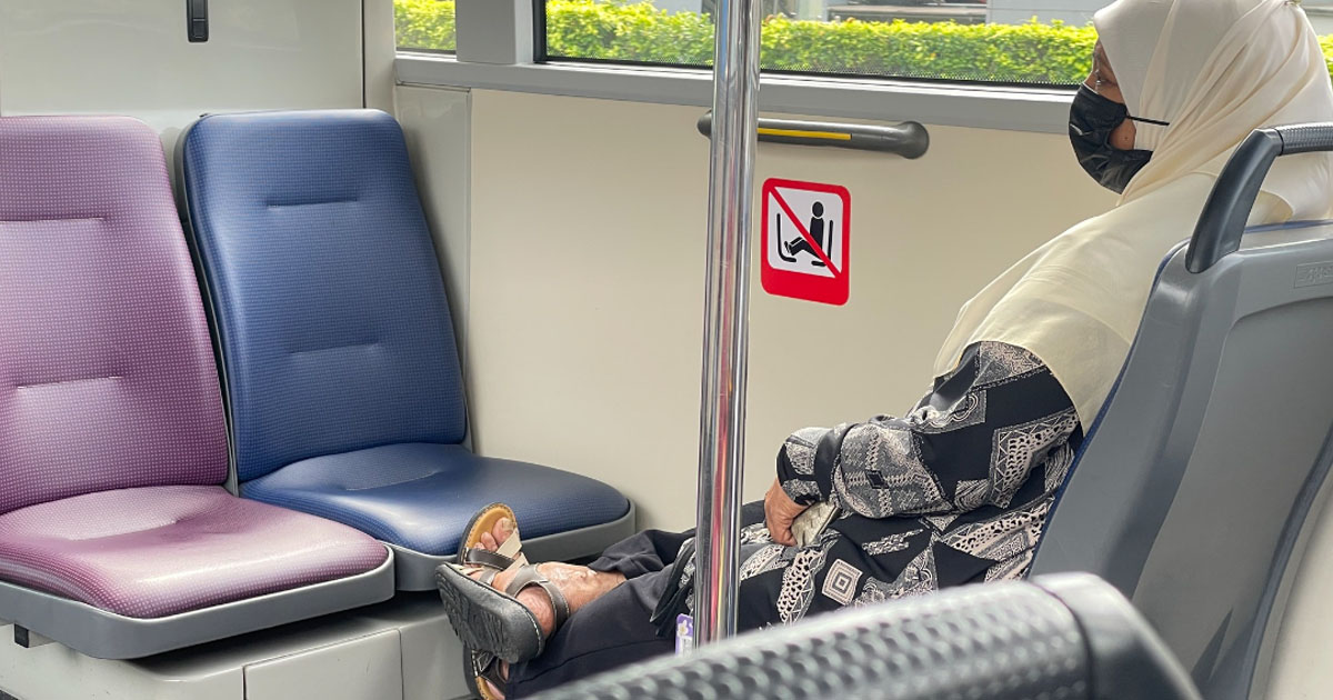 AUNTIE REST HER LEGS ON THE BUS SEAT, STICKER BESIDE HER ARE INSTRUCTIONS